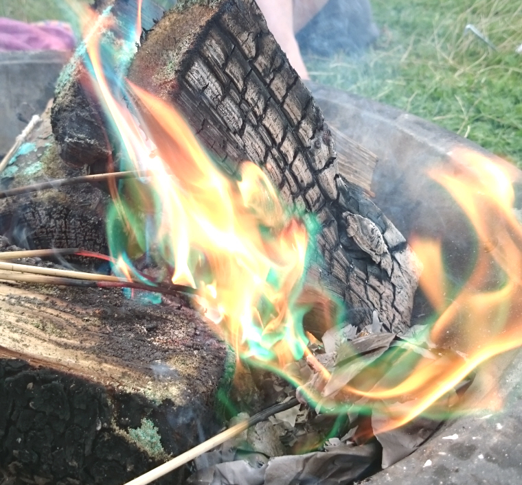 Multicoloured flames around burning wood in a firepit